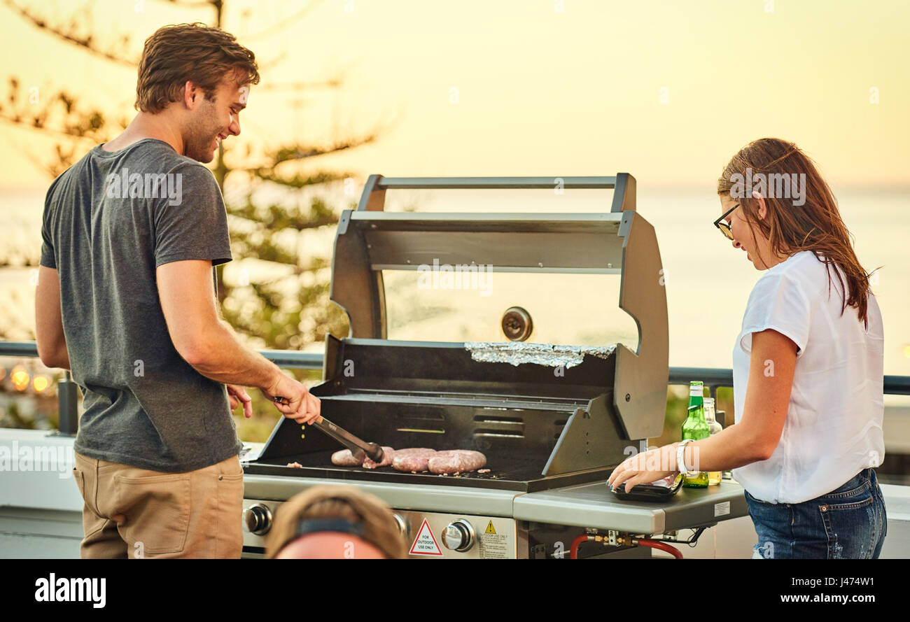 Happy attractive couple standing together on a rooftop barbecue Stock ...