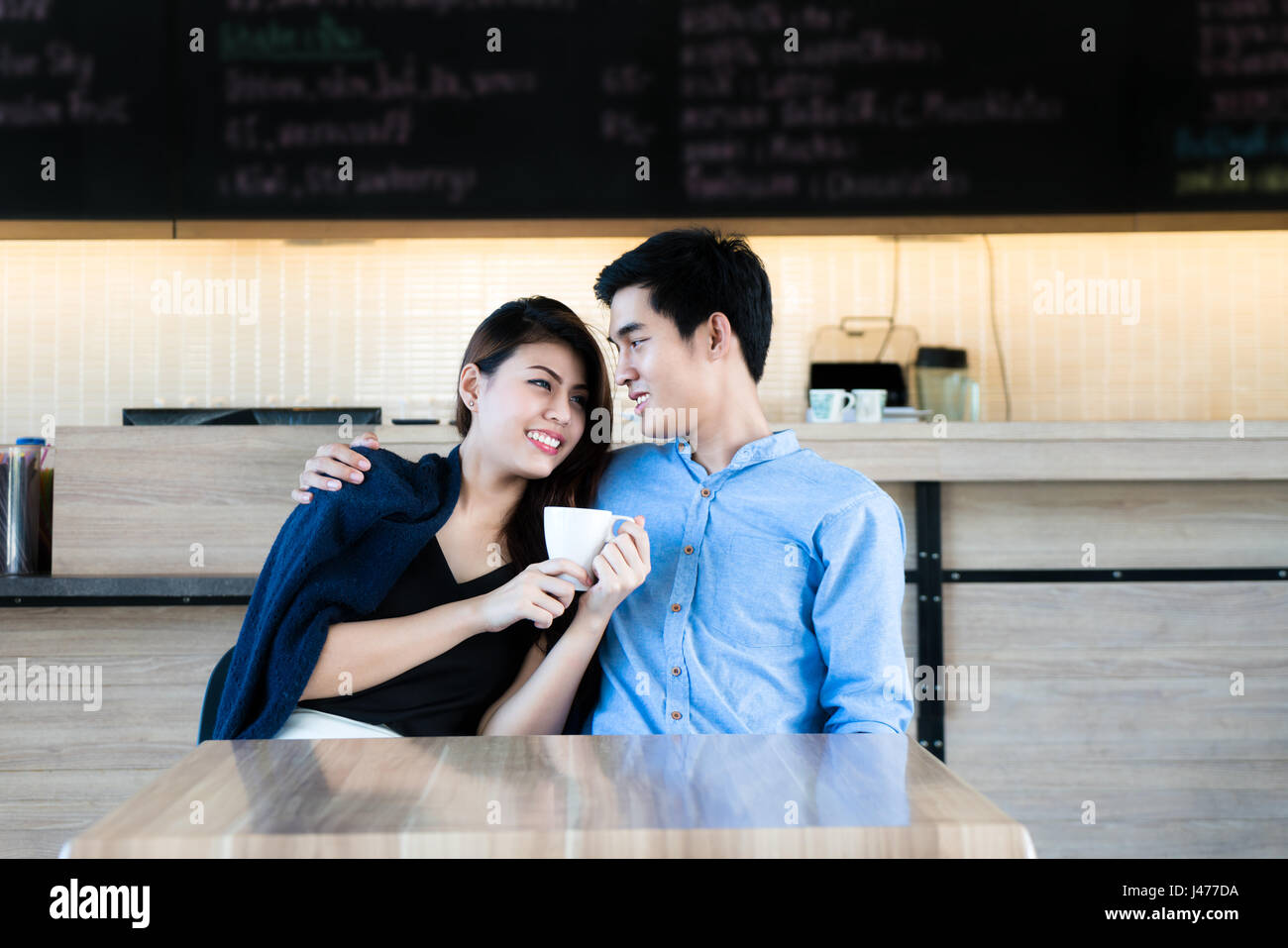 Asian beautiful young couple sitting in a cafe, drinking coffee and ...