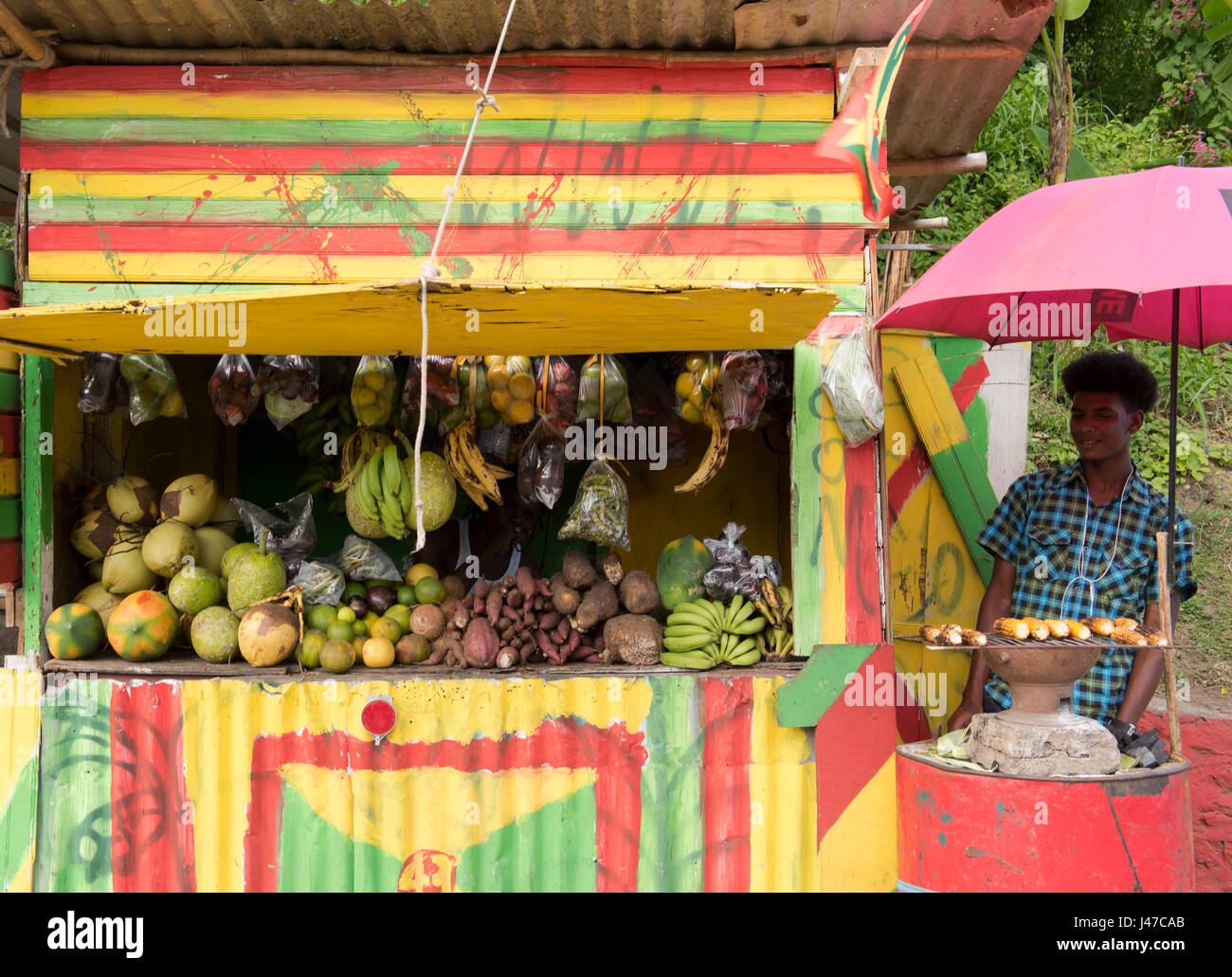 A colourfully painted roadside stand selling fruit and vegetables next ...