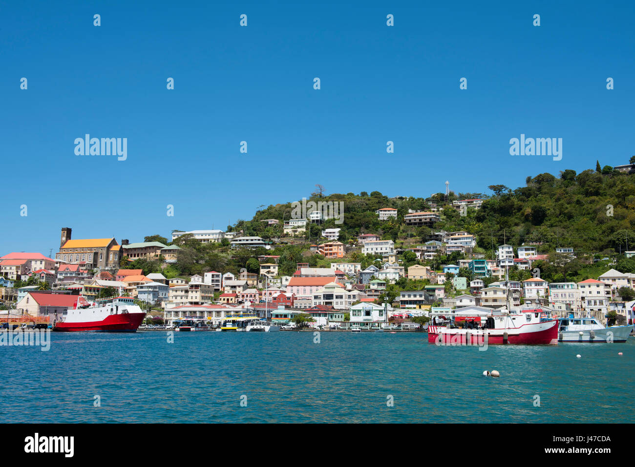 Boats in the Carenage surrounded by colourful buildings on a hill in St ...