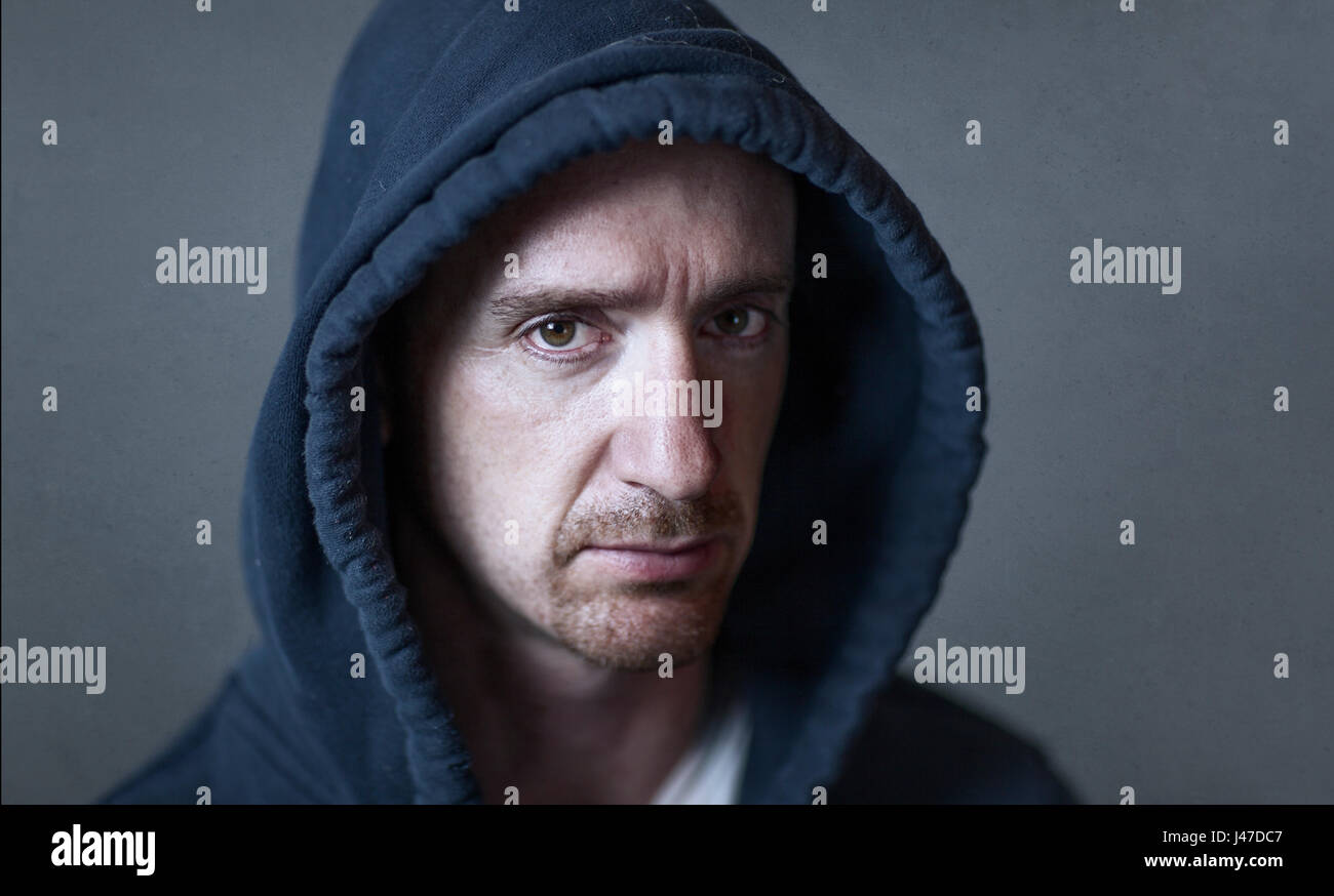 Intense and angry looking homeless man with red goatee in blue hooded ...