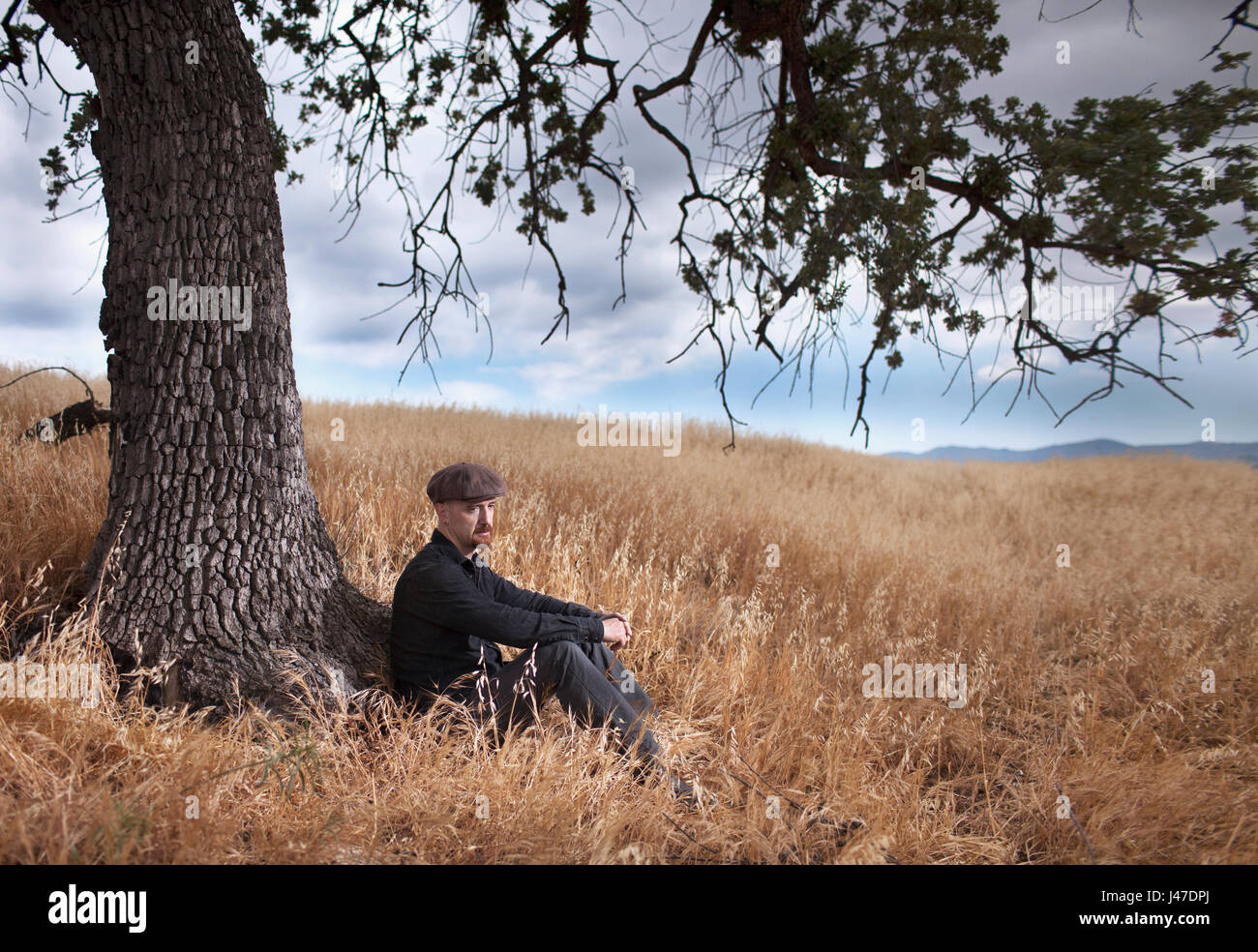 Sad solitary man with a red goatee wearing a black denim jean cowboy ...