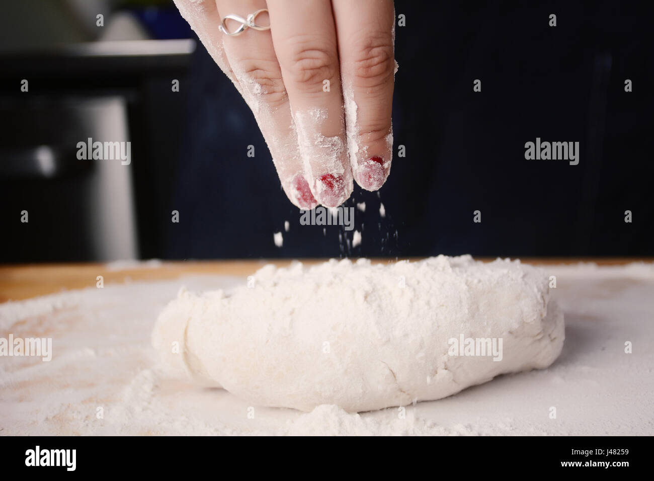 Close up of a woman hand adding flour to dough. Cooking concept Stock ...