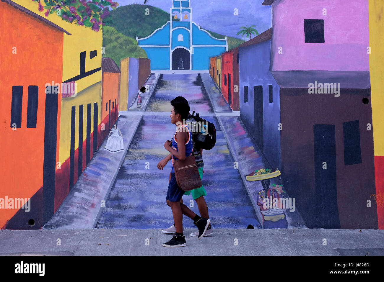 Locals pass by a painted wall in the town of San Andres, located on the ...