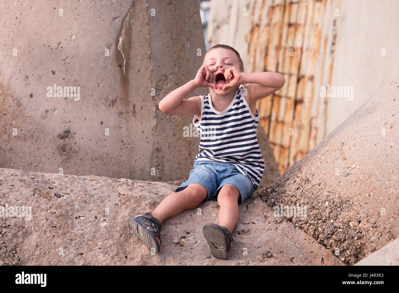 funny screaming little boy sitting on a breakwater on a pier Stock ...