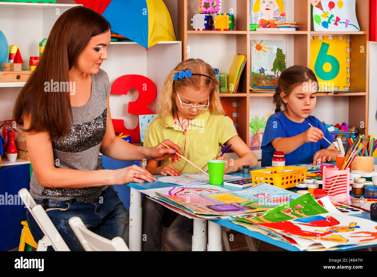 Small students with teacher painting in art school class Stock Photo ...