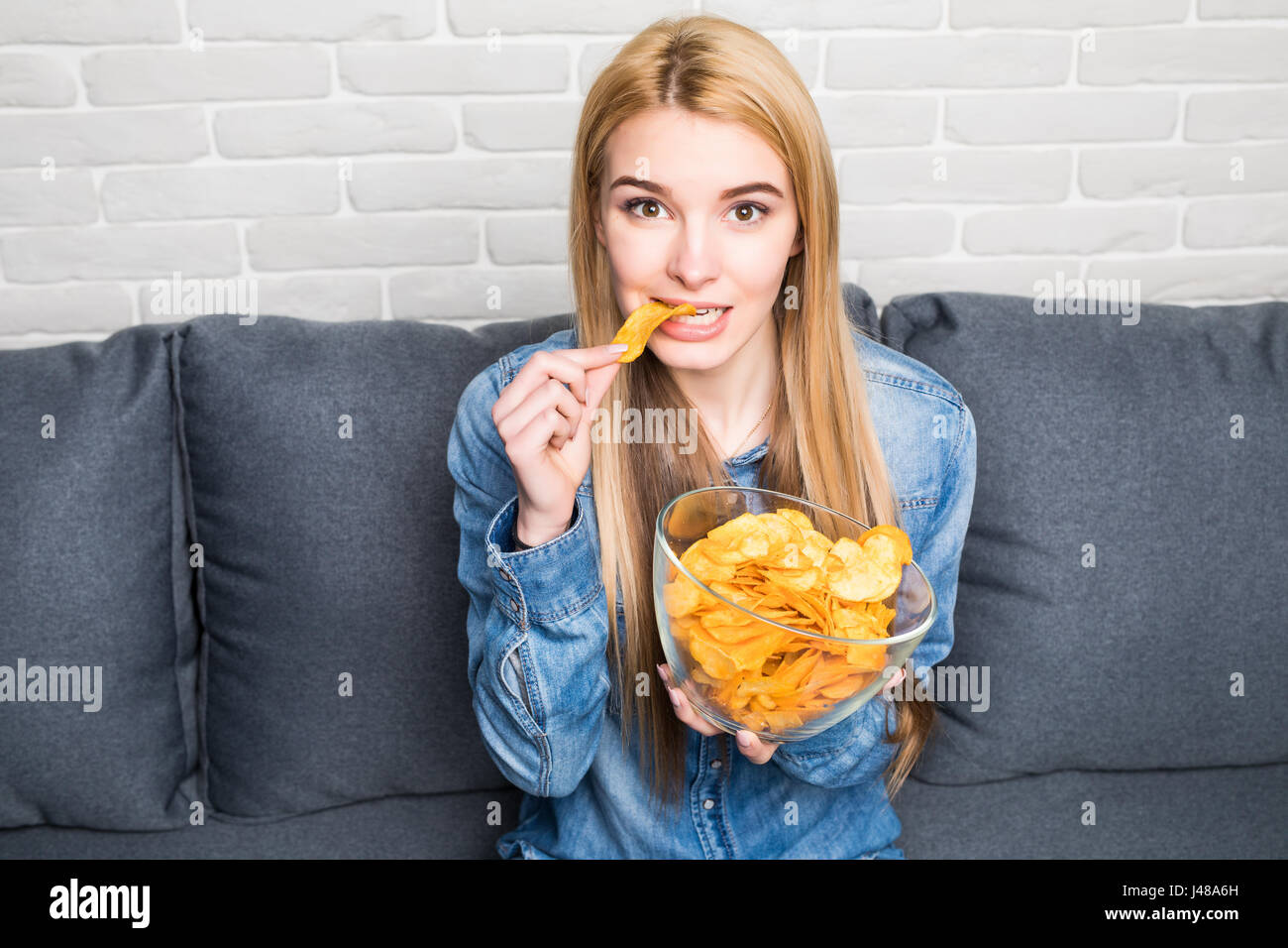 Portrait of smiling girl eating chips at home Stock Photo - Alamy