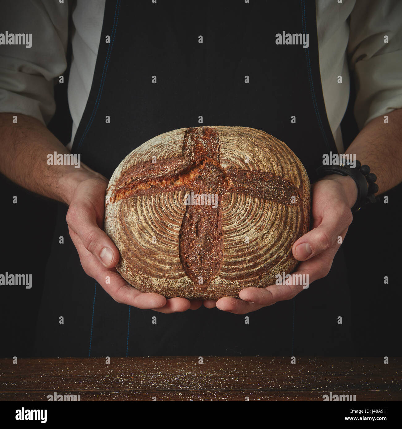 Close-up of a man's hand holding a round dark bread Stock Photo - Alamy