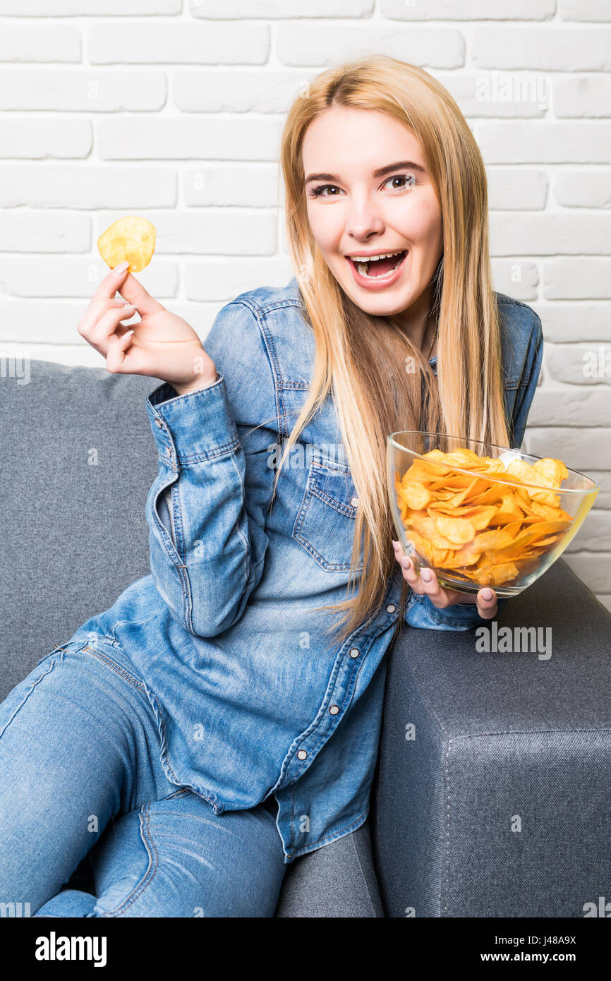 Young woman watching TV and eating chips Stock Photo - Alamy