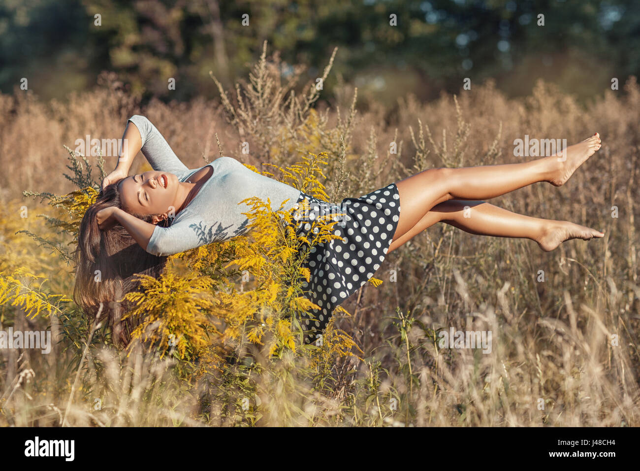 Girl with long hair flying over the meadow on the back Stock Photo - Alamy