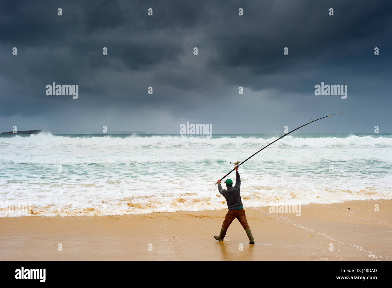 Fisherman fishing on the beach in a stormy weather Stock Photo - Alamy