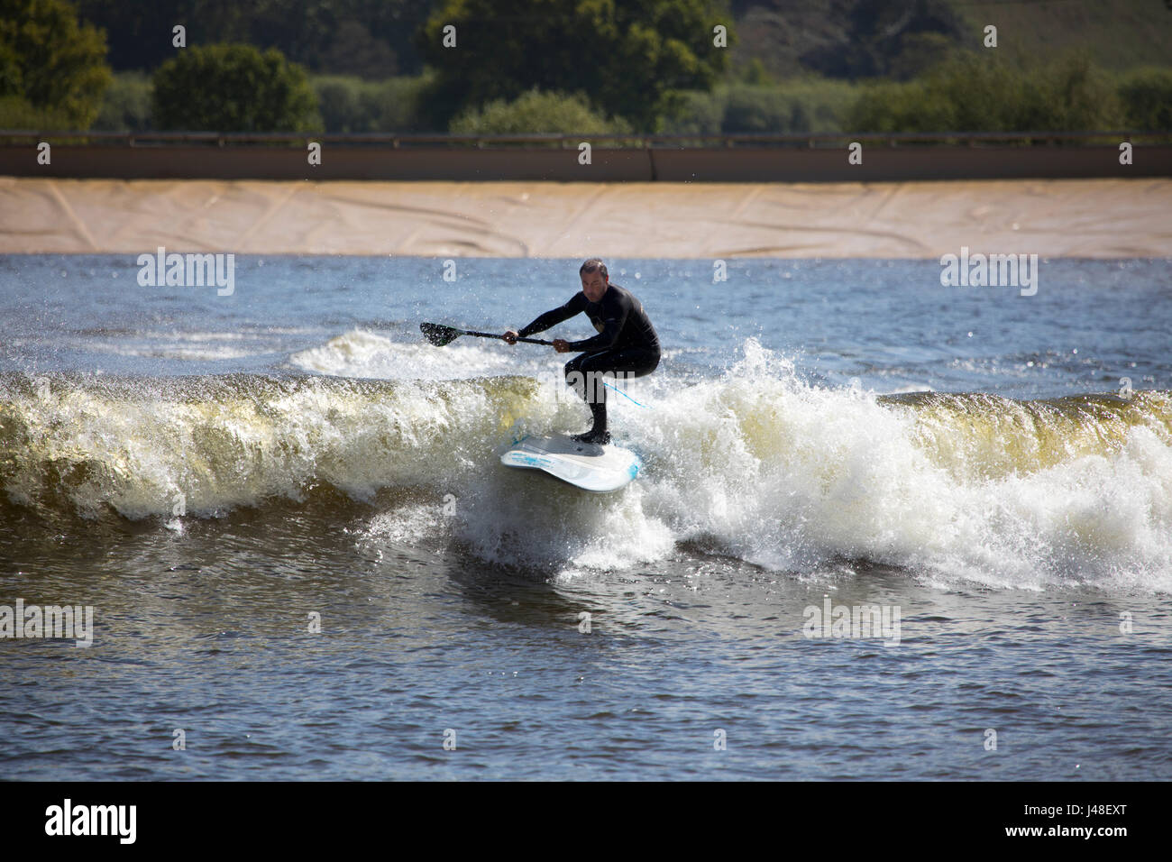 A paddle boarder surfing at artificial wave pool in the Conwy Valley ...