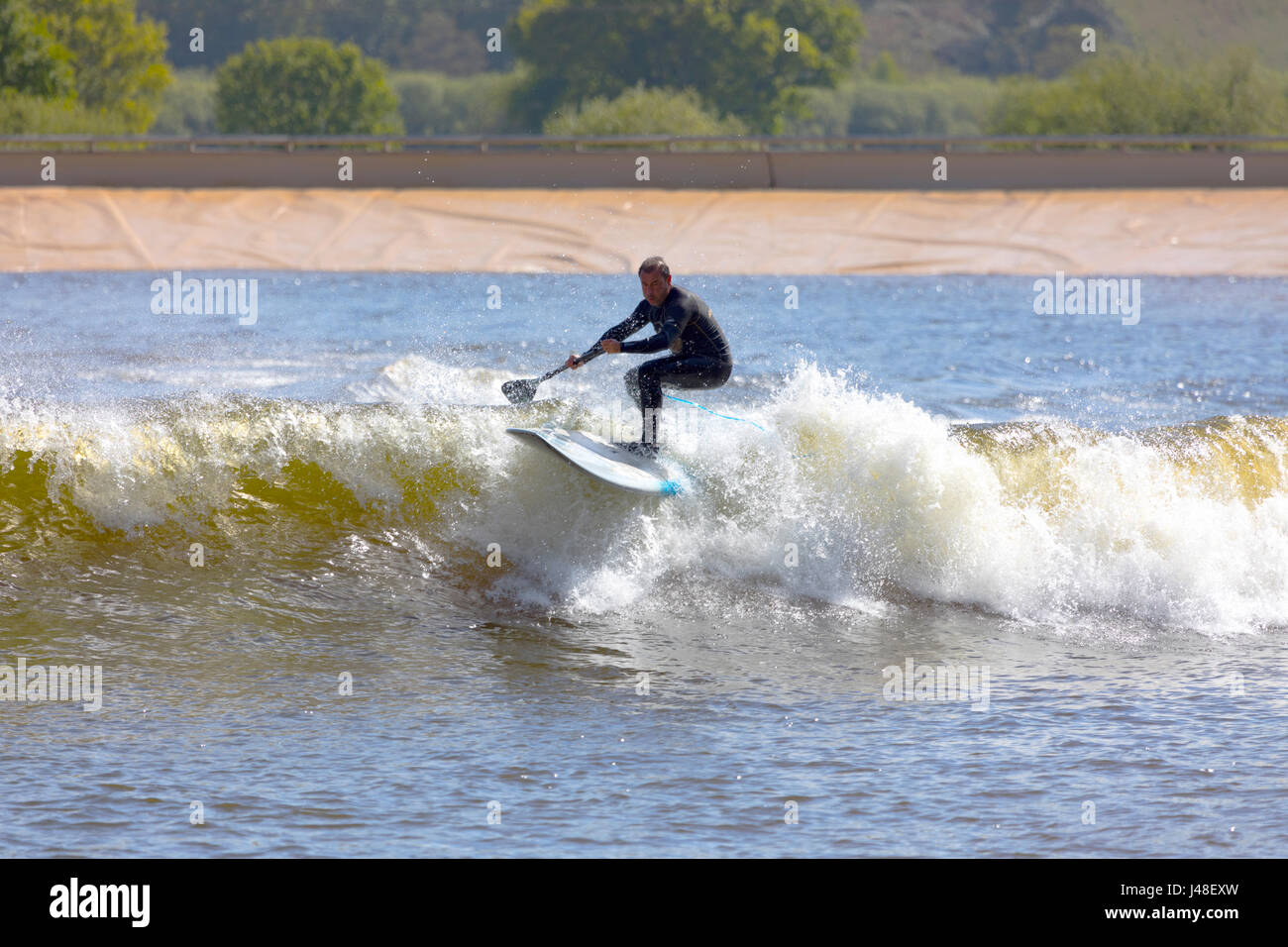 A paddle boarder surfing at artificial wave pool in the Conwy Valley ...