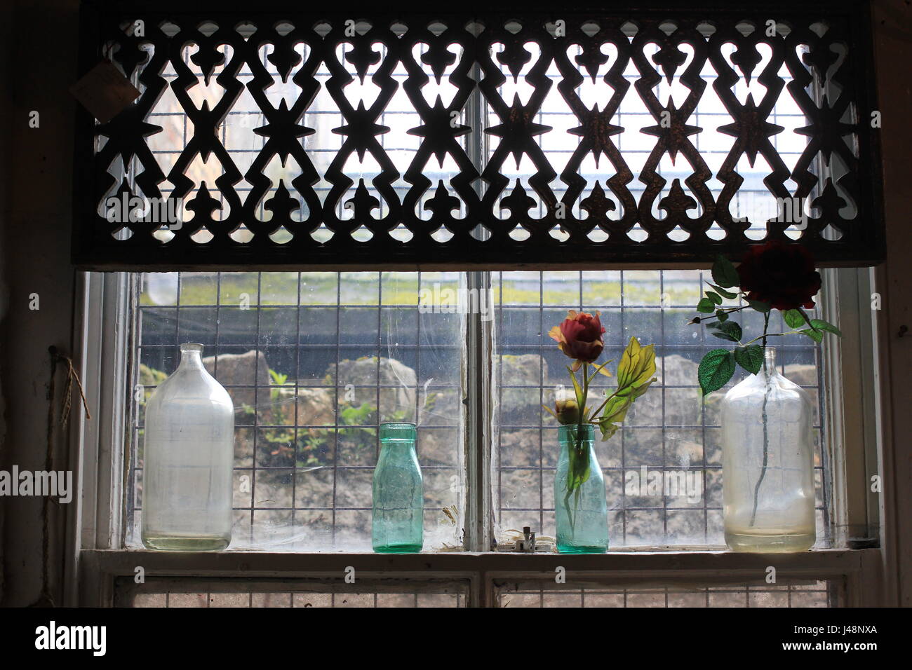 fretwork window with glass bottles and flowers Stock Photo - Alamy