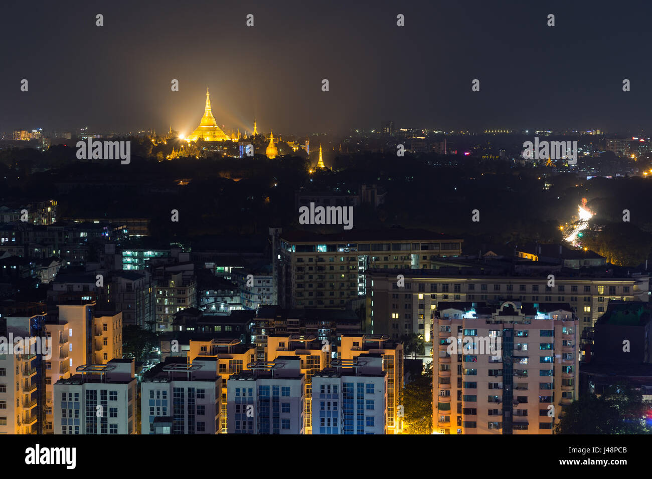 Apartment buildings and lit Shwedagon Pagoda in Yangon, Myanmar, viewed ...
