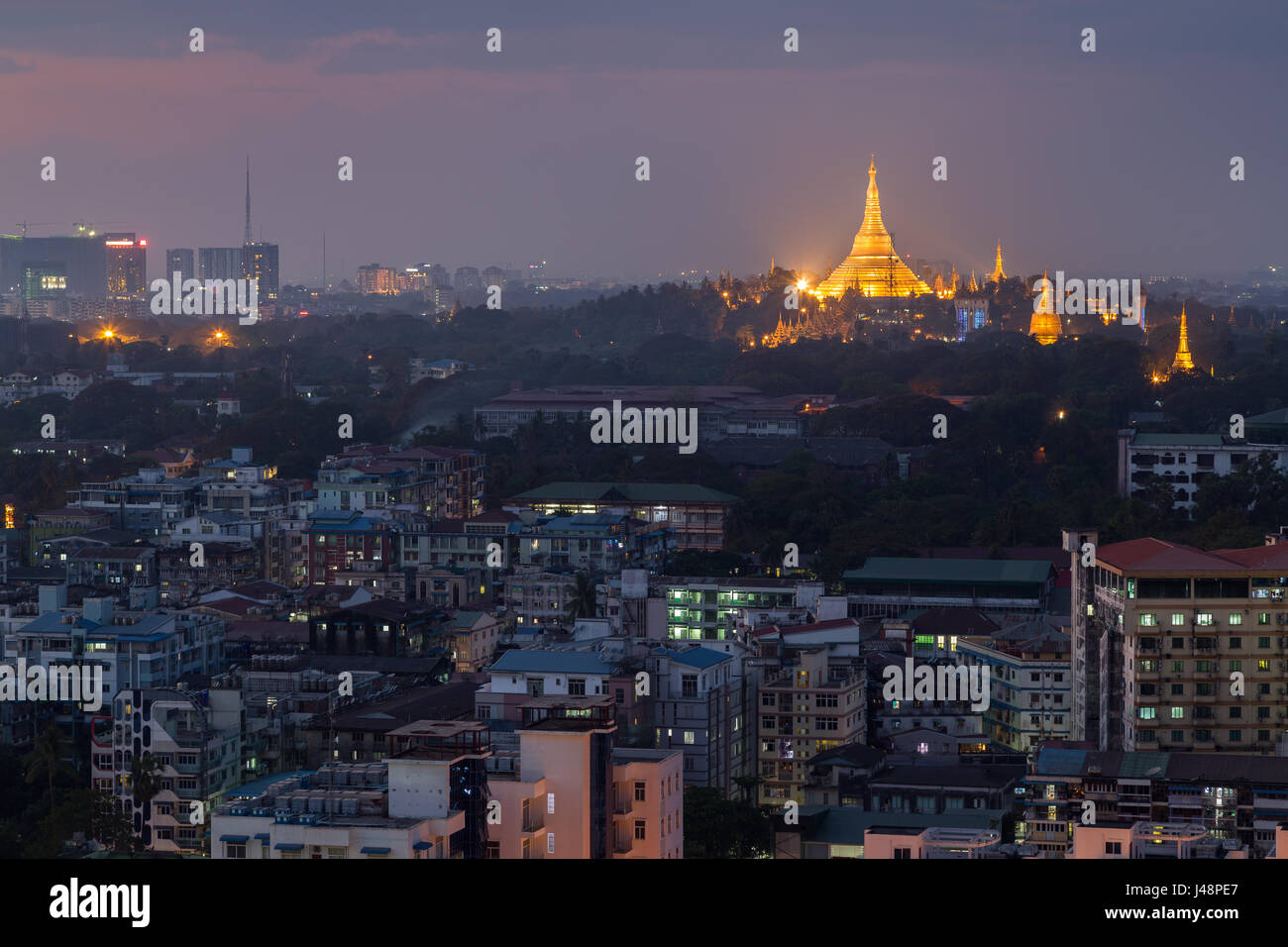 Apartment buildings and lit Shwedagon Pagoda in Yangon, Myanmar, viewed ...