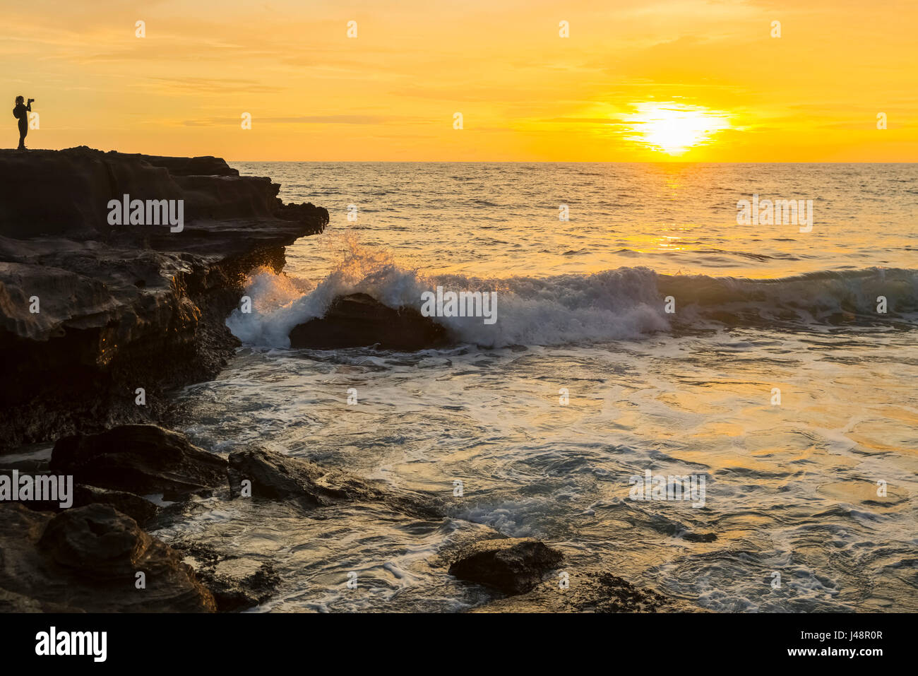 Golden sunset over the ocean with a view of the coastline; Bali Island ...