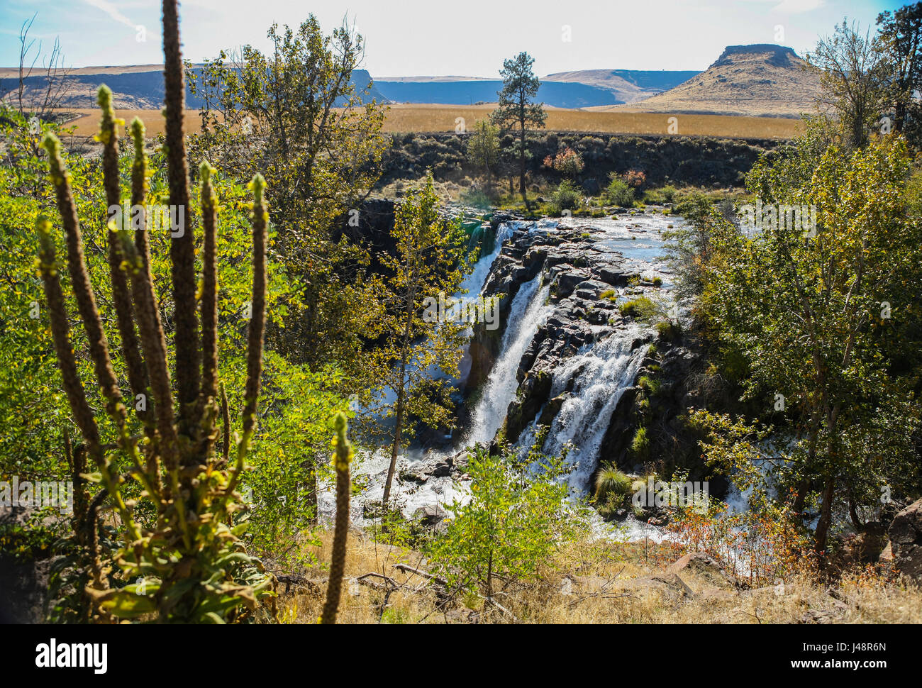 Waterfall over a cliff with a field and plateaus in the distance Stock ...