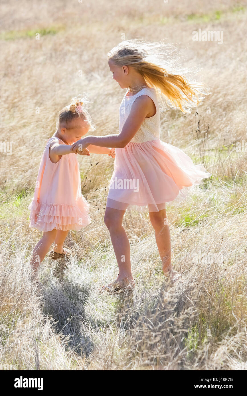 Two young girls dancing in a field of long grass; Washington, United ...