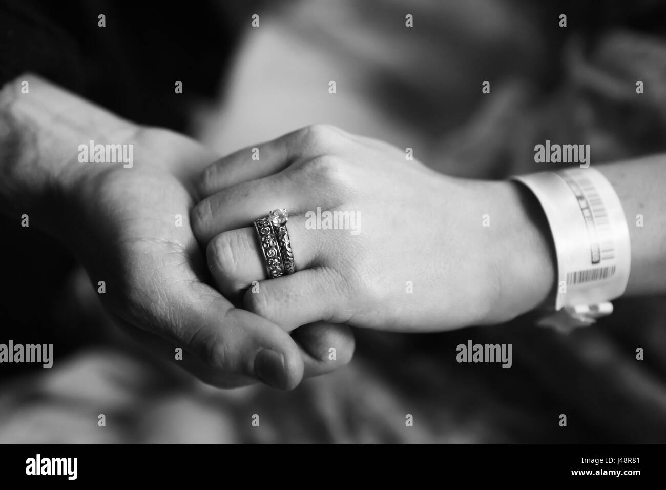 A man and woman hold hands with a medical ID bracelet on the woman's ...