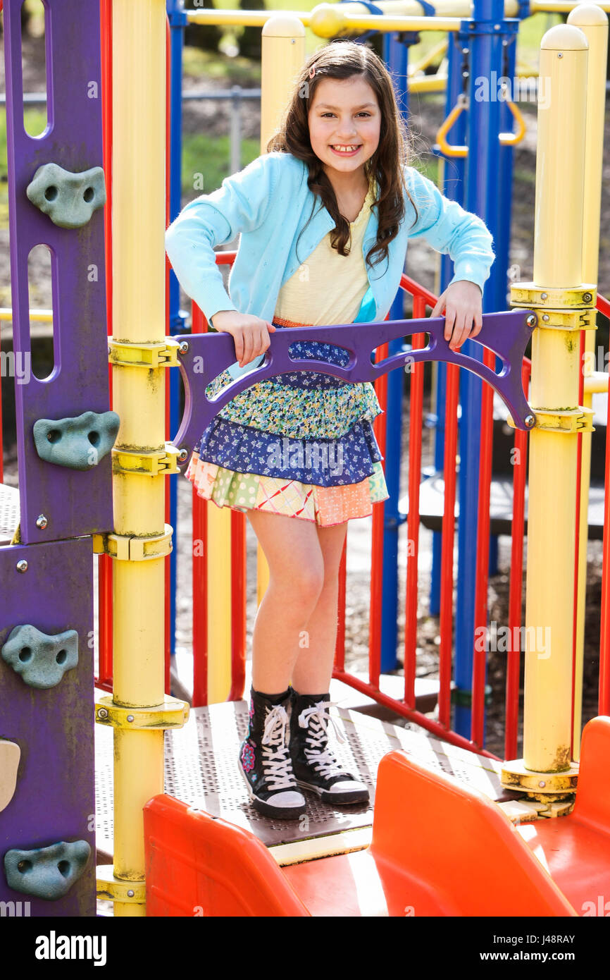 A young girl posing for the camera while playing at the playground ...
