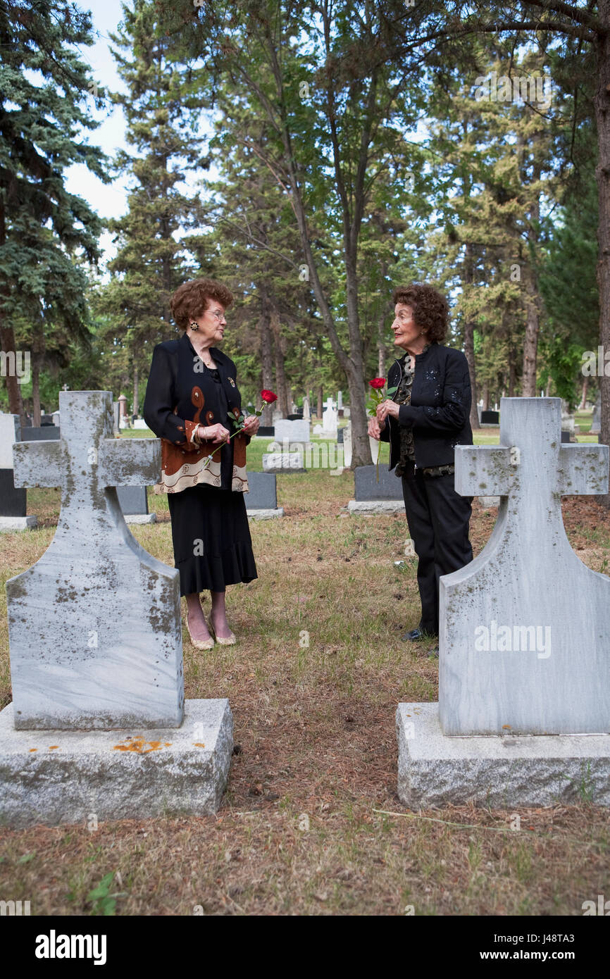 Two Women Holding Single Red Roses At A Grave In A Cemetery; Edmonton ...