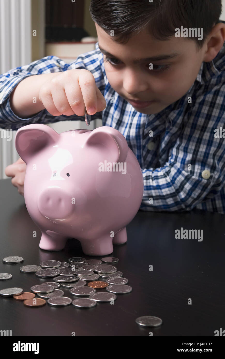 Boy Depositing Coins Into A Piggy Bank; Laval, Quebec, Canada Stock ...