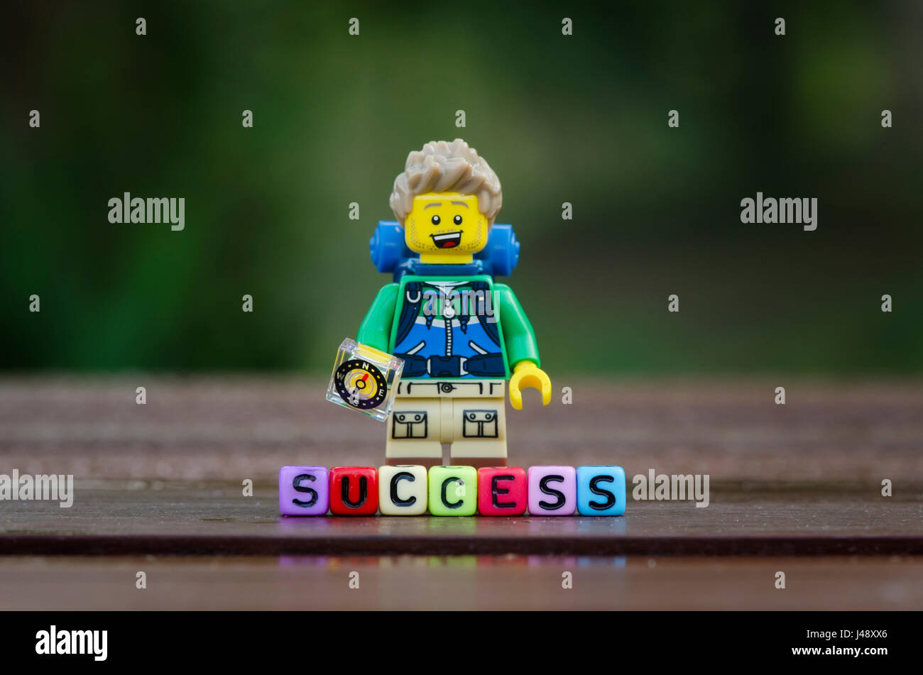 Lego hiker holding compass standing behind word success using colorful ...
