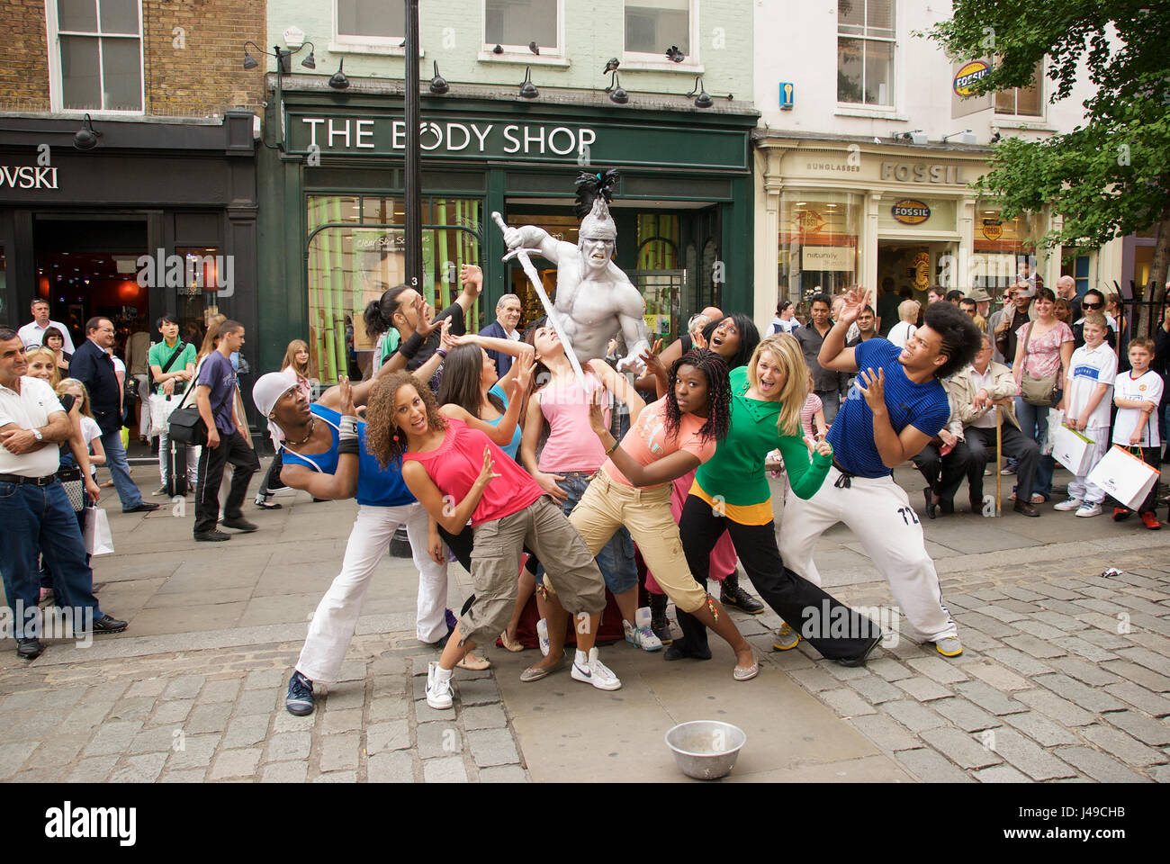 Group of young dancers interacting with a street performer on the ...