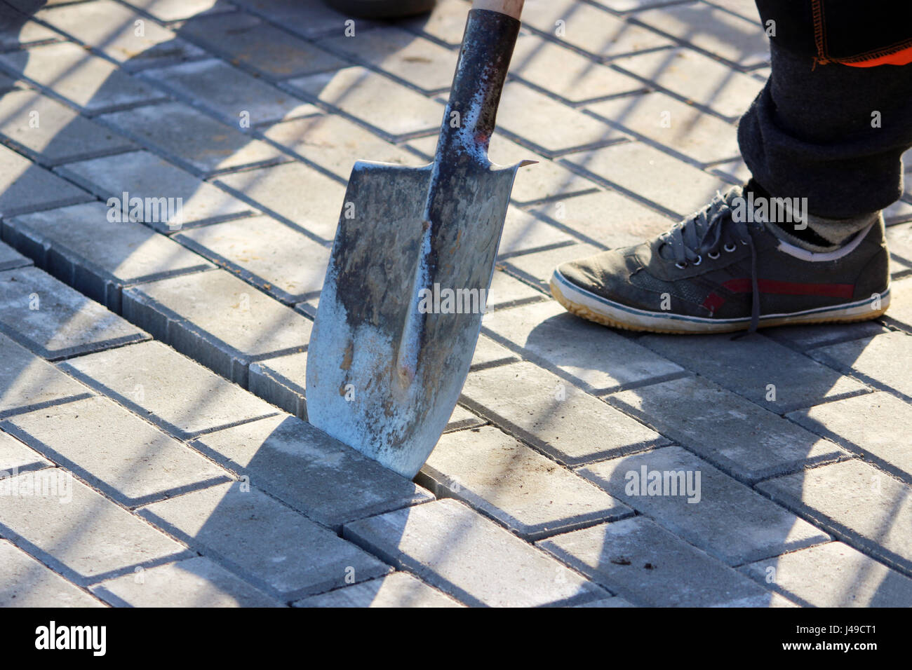 Repair of the sidewalk. The working mason with the help of a shovel ...