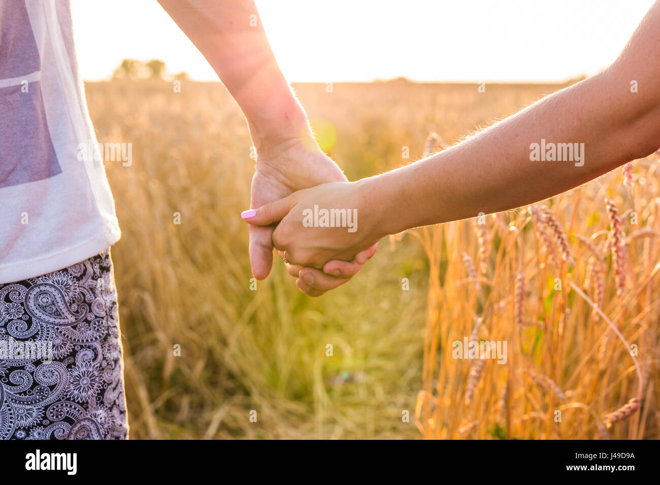 Closeup of couple holding hands in nature sunrise Stock Photo - Alamy