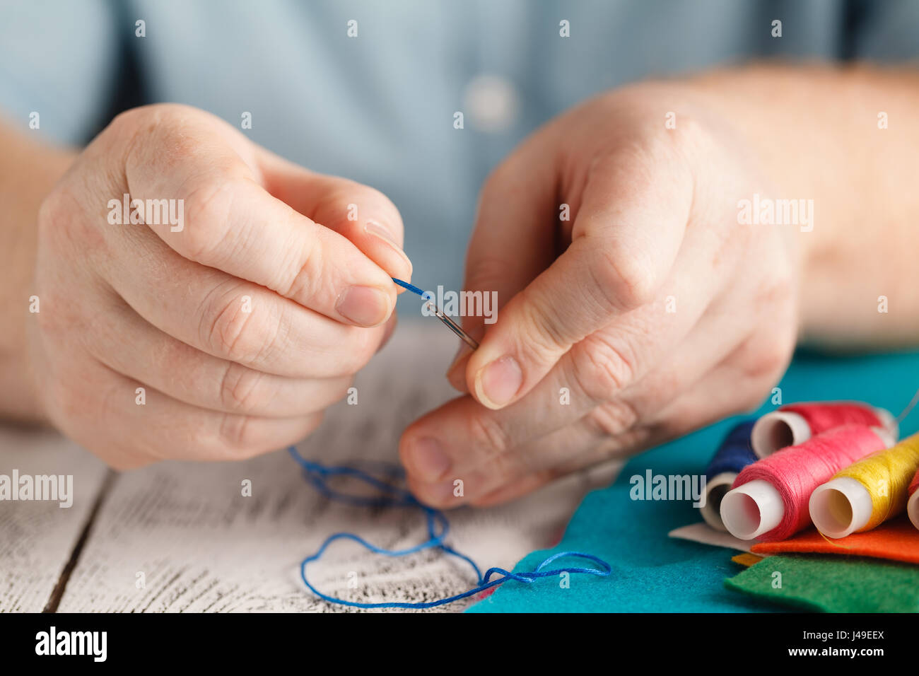 Thread into the needle. Close-up of man pulling thread into the needle ...