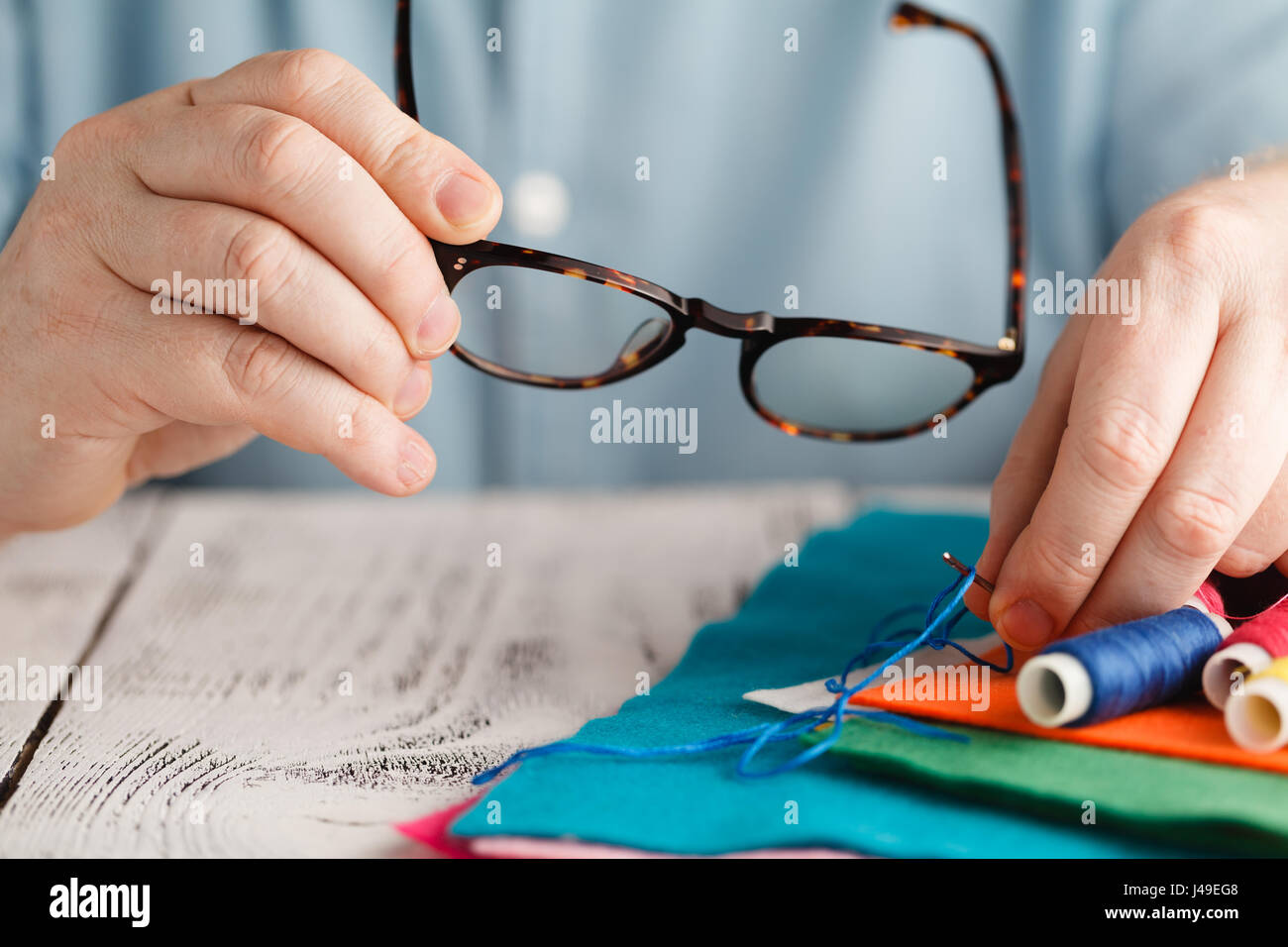 old man looking on sew needle throw glasses Stock Photo - Alamy