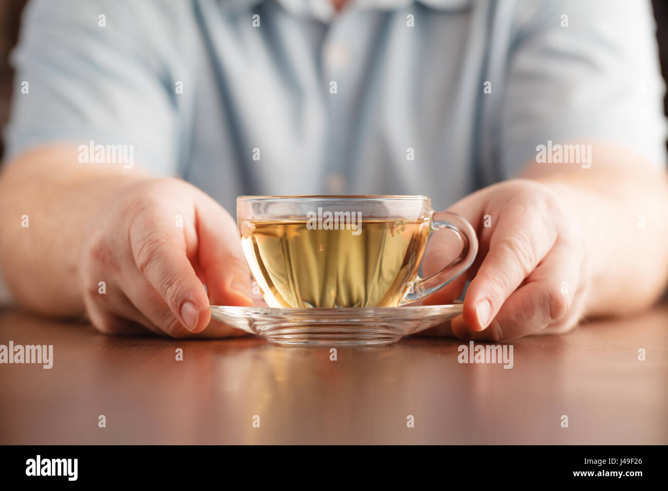 Man hold cup in hand and offer tea Stock Photo - Alamy