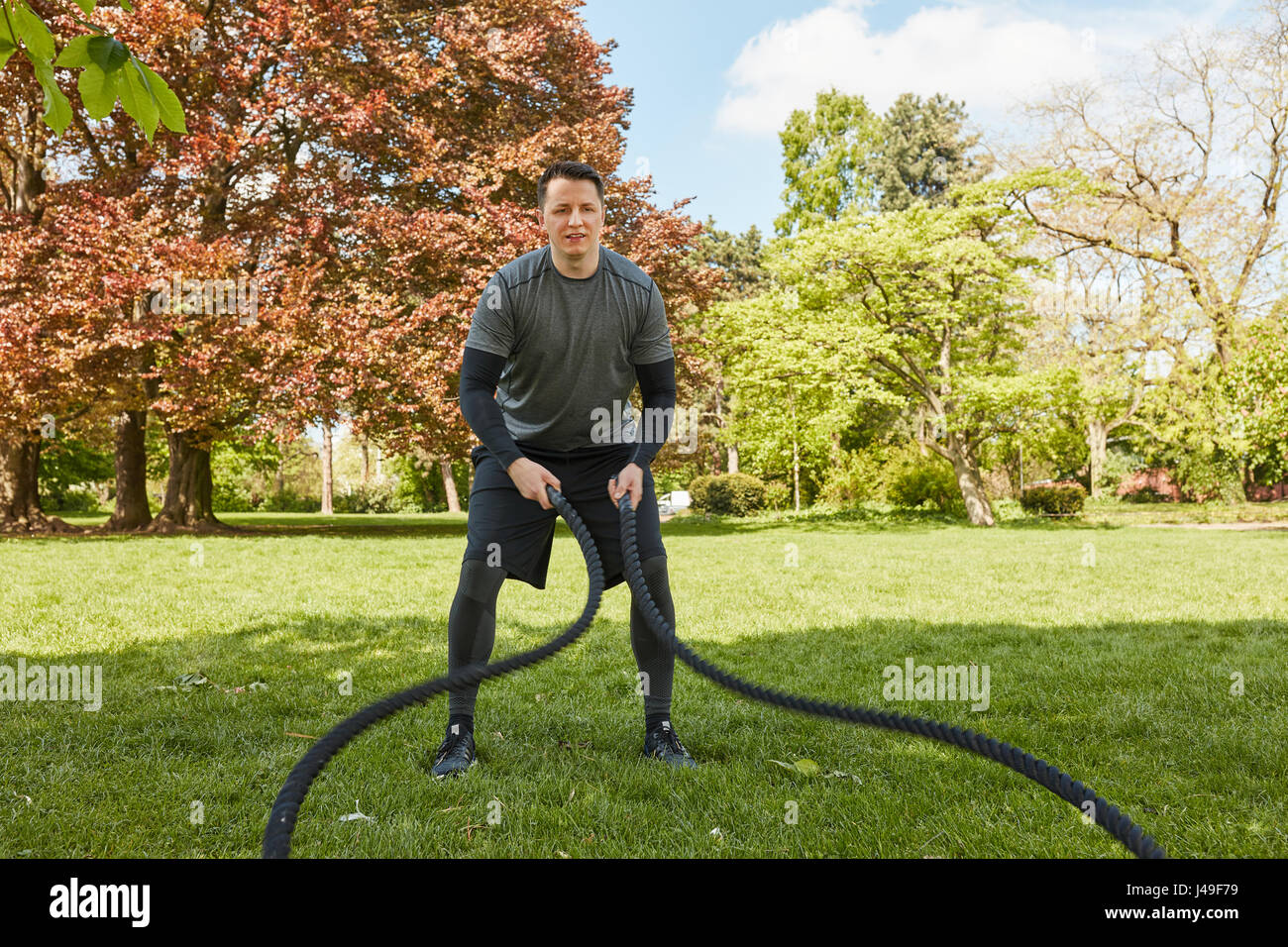 Man makes battle rope training at park in summer Stock Photo - Alamy