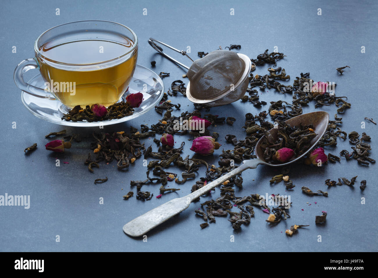 Spilled green tea with a rose and a strainer Stock Photo - Alamy