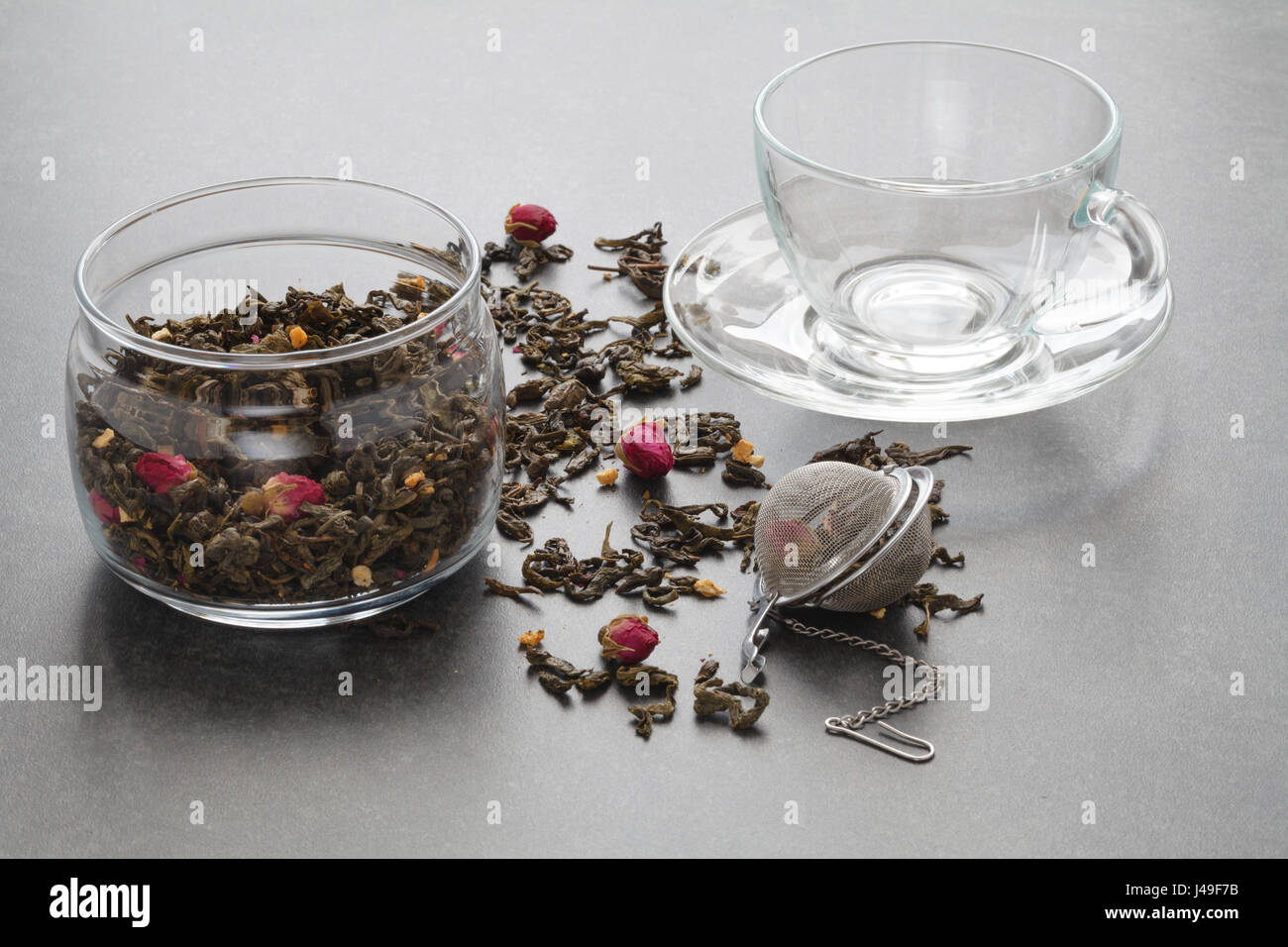 Spilled green tea with a rose and a strainer Stock Photo - Alamy