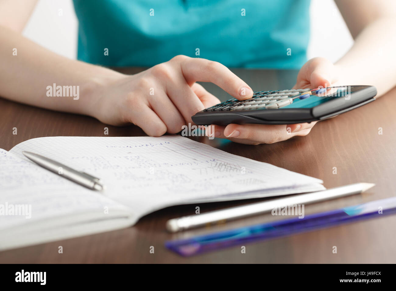 girl solving a math problem in notepad on table Stock Photo - Alamy
