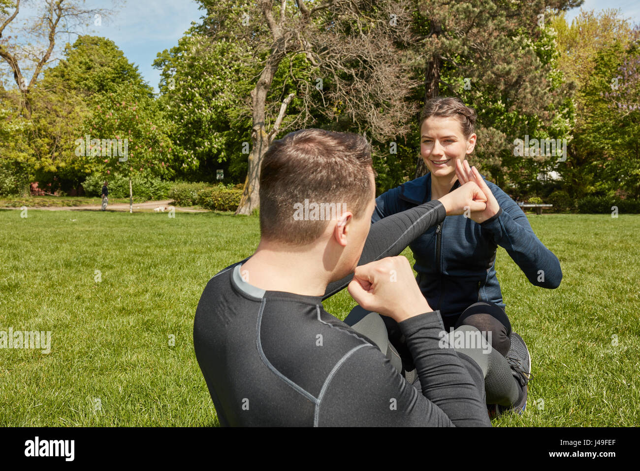 Man makes sit-ups with motivation from Personal Trainer at the park ...