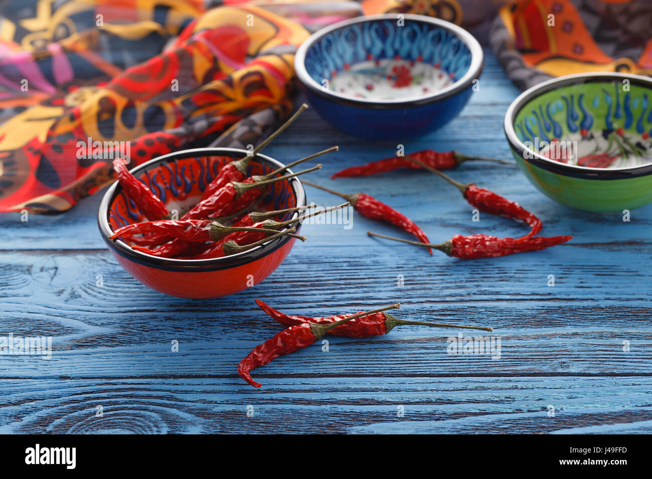 Red pepper on blue wooden table with silk scarf Stock Photo - Alamy