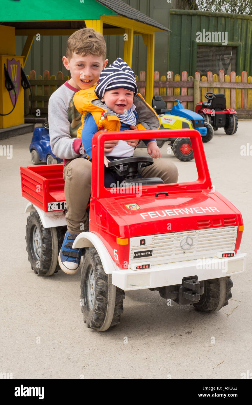 Brothers riding on a pedal car at Woodlands Family Theme Park, Totnes ...