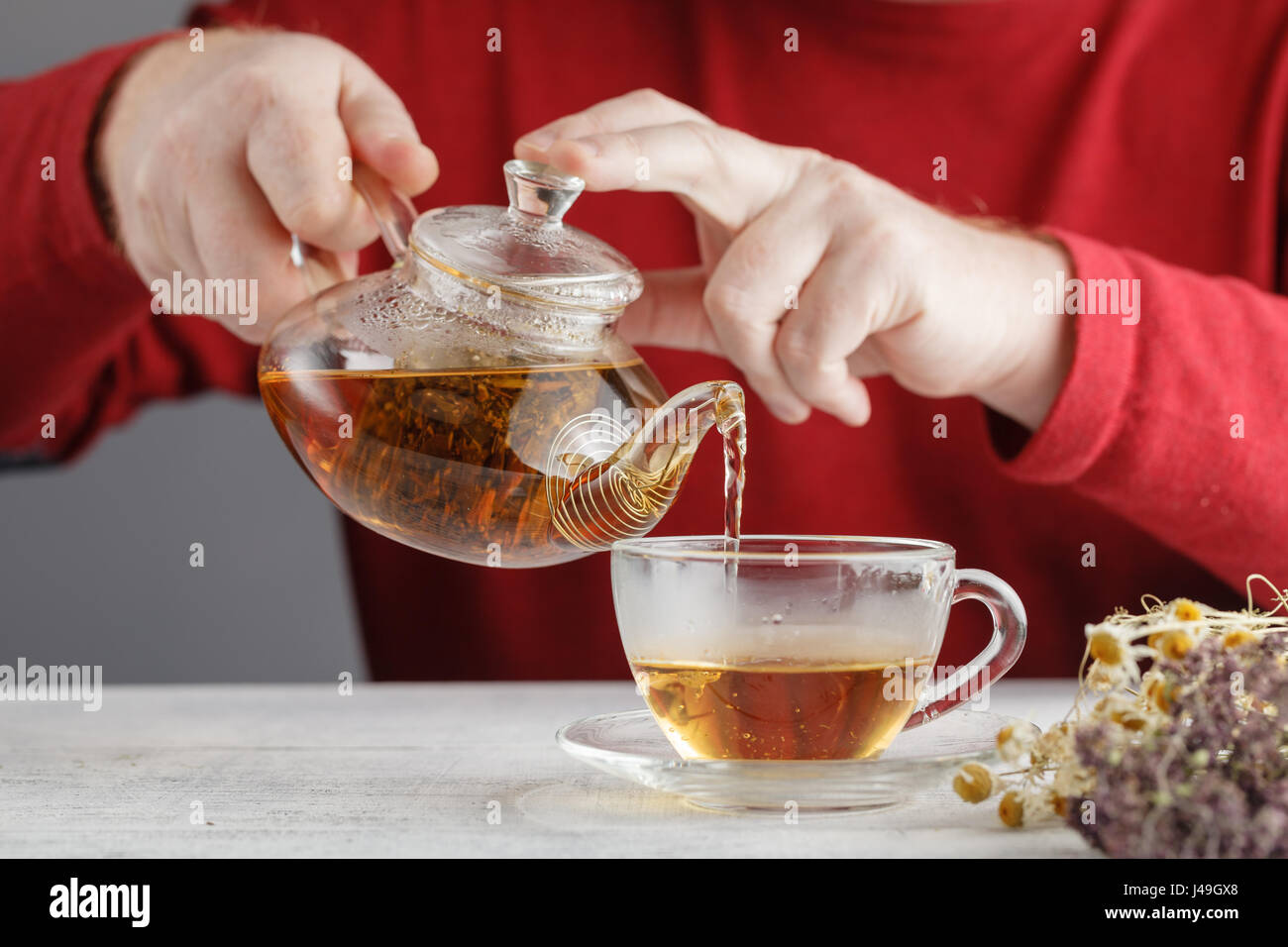 male pouring From transparent glass teapot pour black tea in glass mug ...