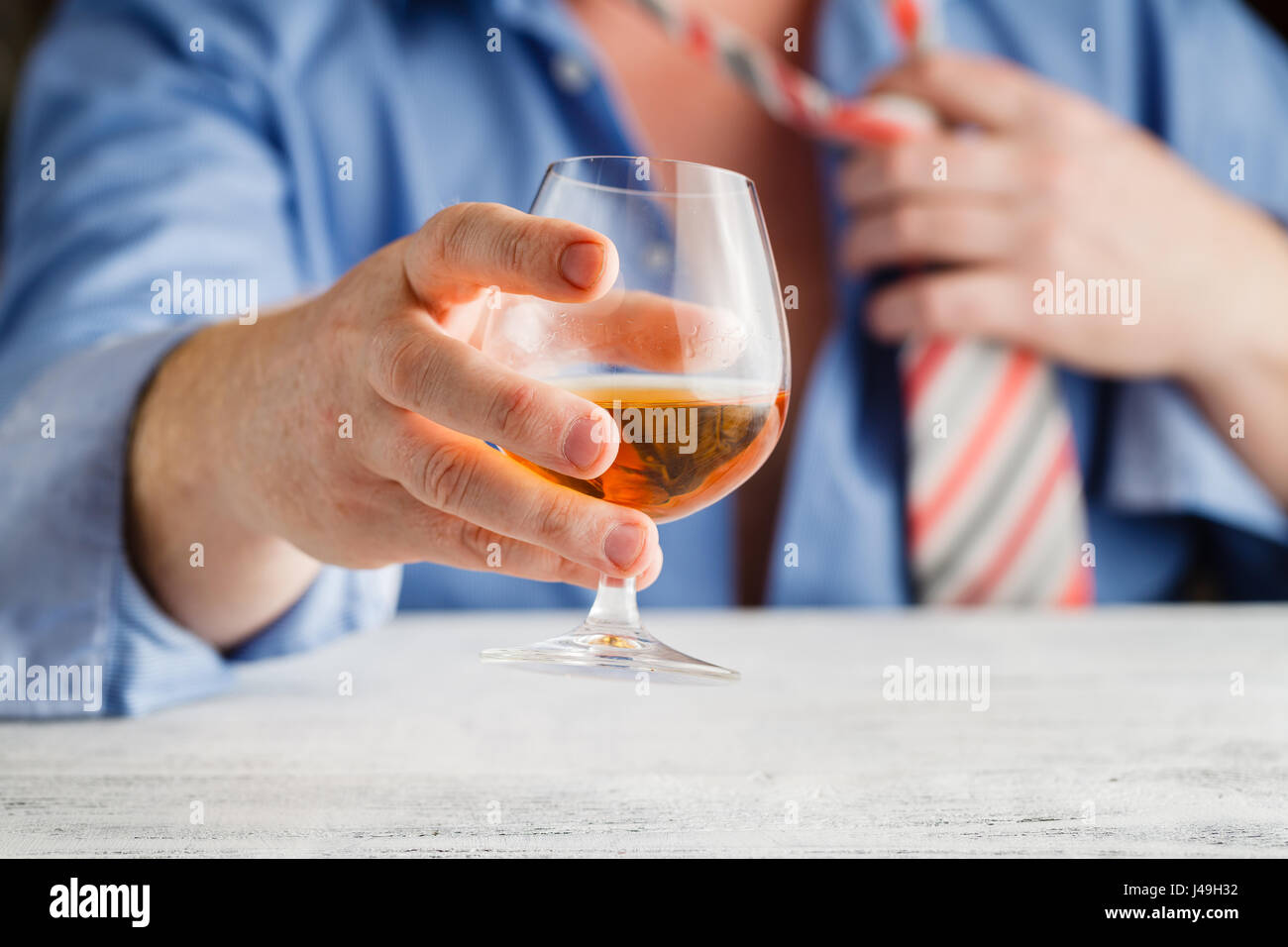 Hands with glass of cognac. Focus on hand with glass Stock Photo - Alamy
