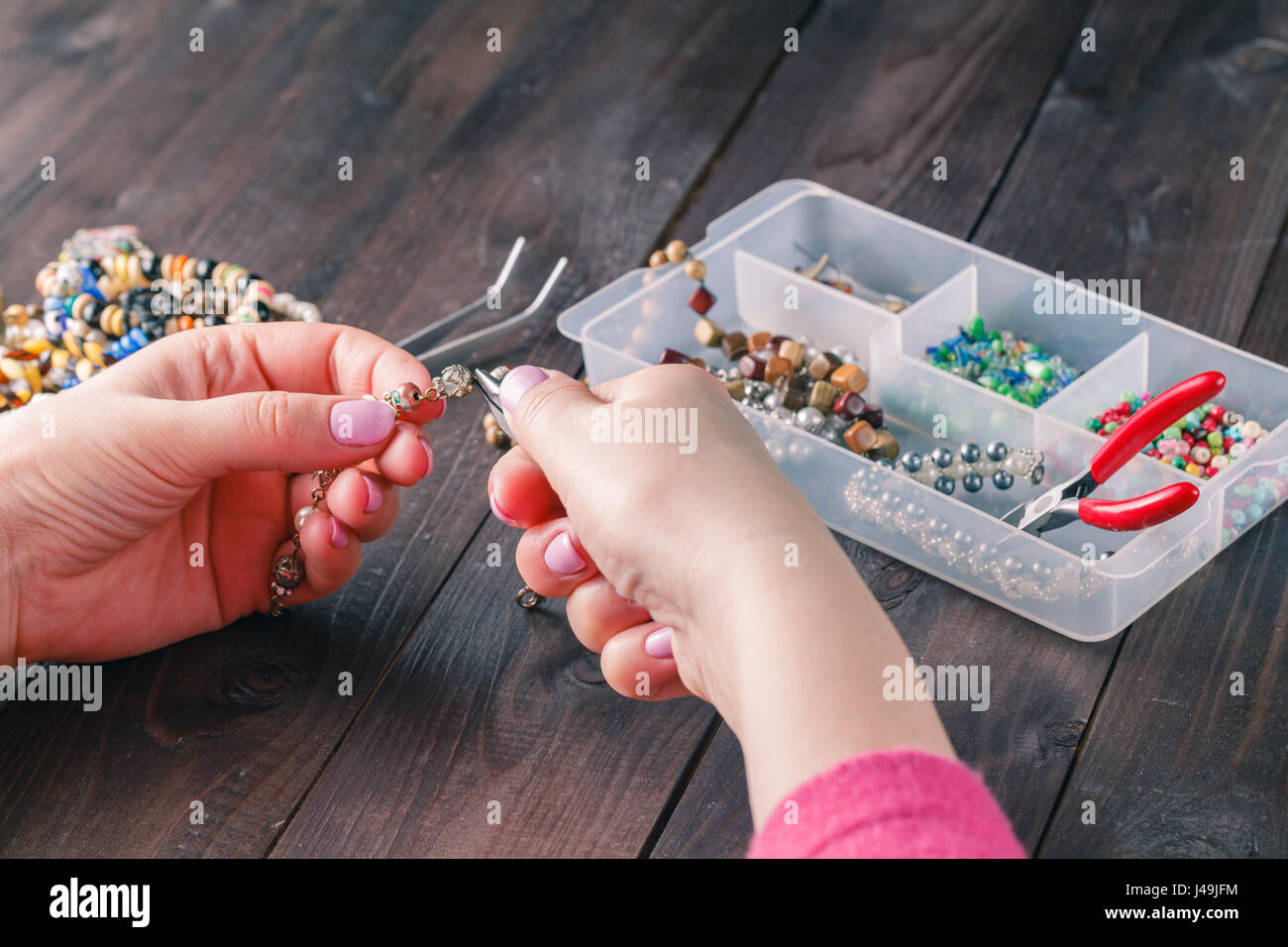 Woman making beads. Box with beads, spool of thread, plier and glass ...