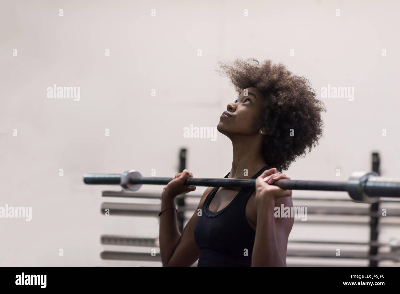 Young Cute african american sport woman in fitness room lifting empty ...