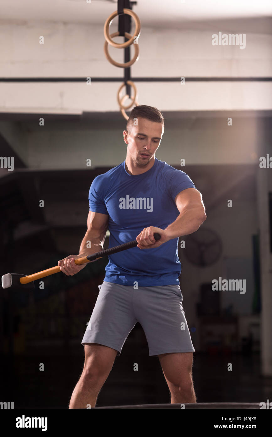 Sledgehammer Tire Hits young muscular man workout at gym with hammer ...