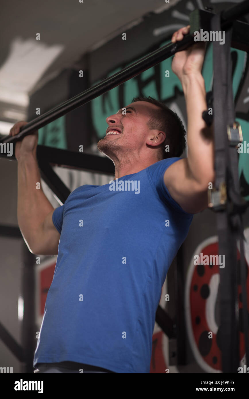 strong young man doing pull ups on a bar in a gym Stock Photo - Alamy