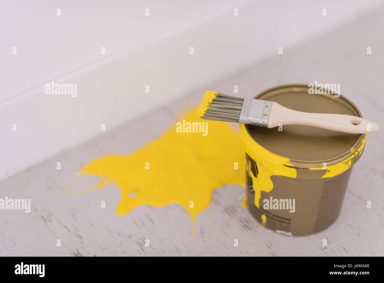 Yellow paint tin can with brush on top with yellow strokes on the ...