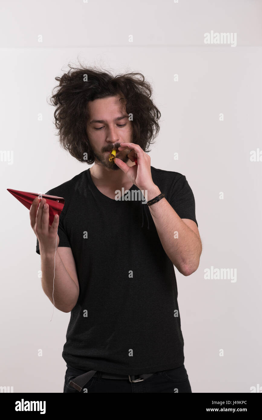 Portrait of a man in party hat blowing in whistle isolated on a white ...