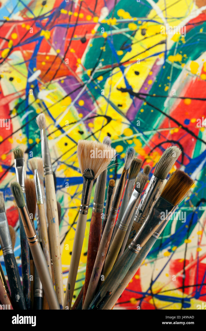A collection of well used art paint brushes with a highly colourful ...
